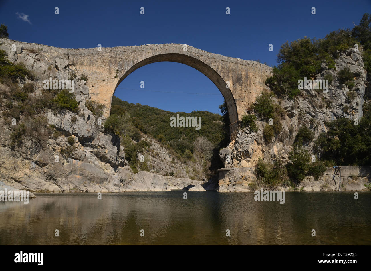 The large stone masonry arch bridge span over the river Llierca in ...