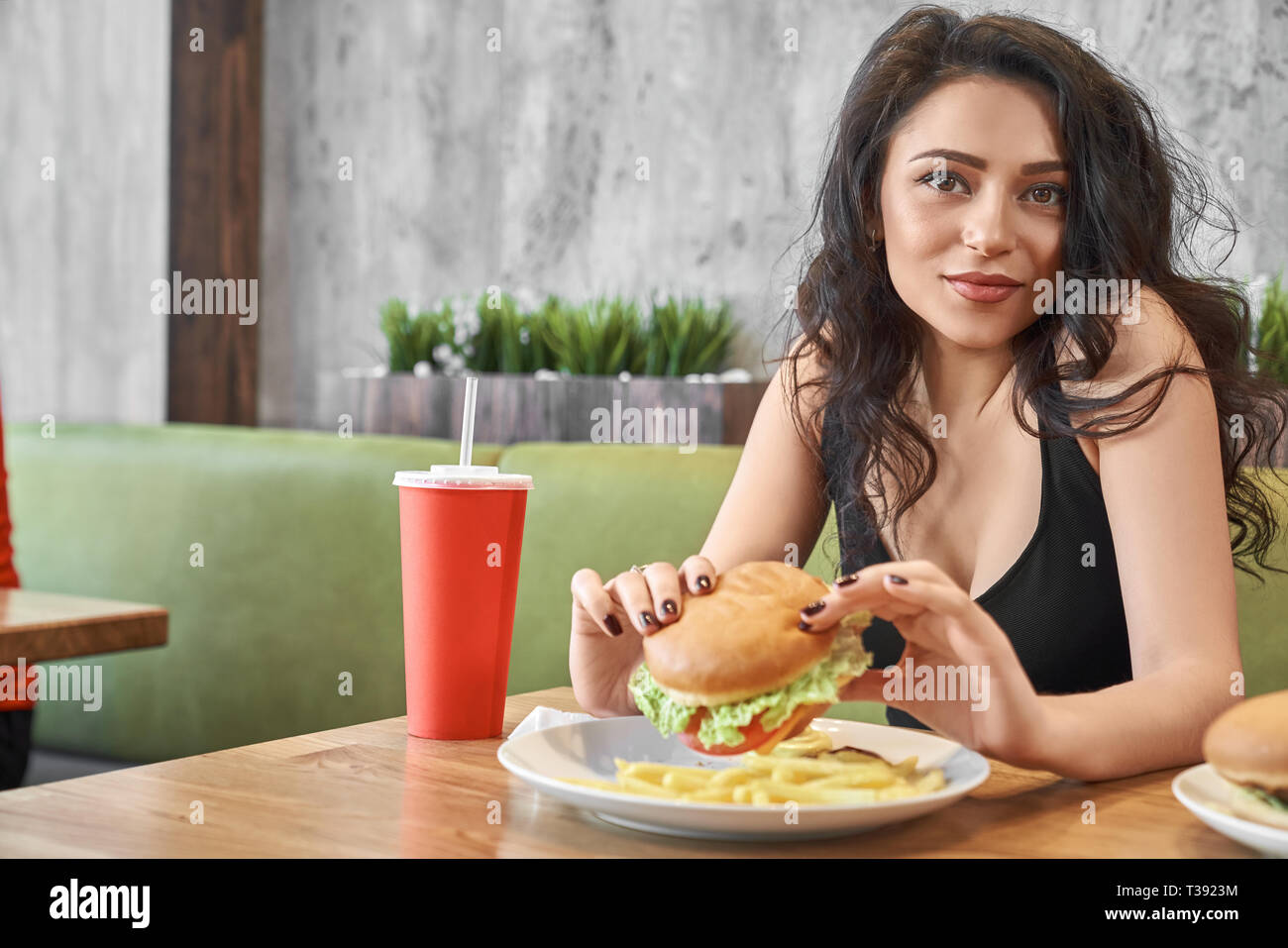 Pretty young female student having lunch in cafe. Brunette sitting at ...