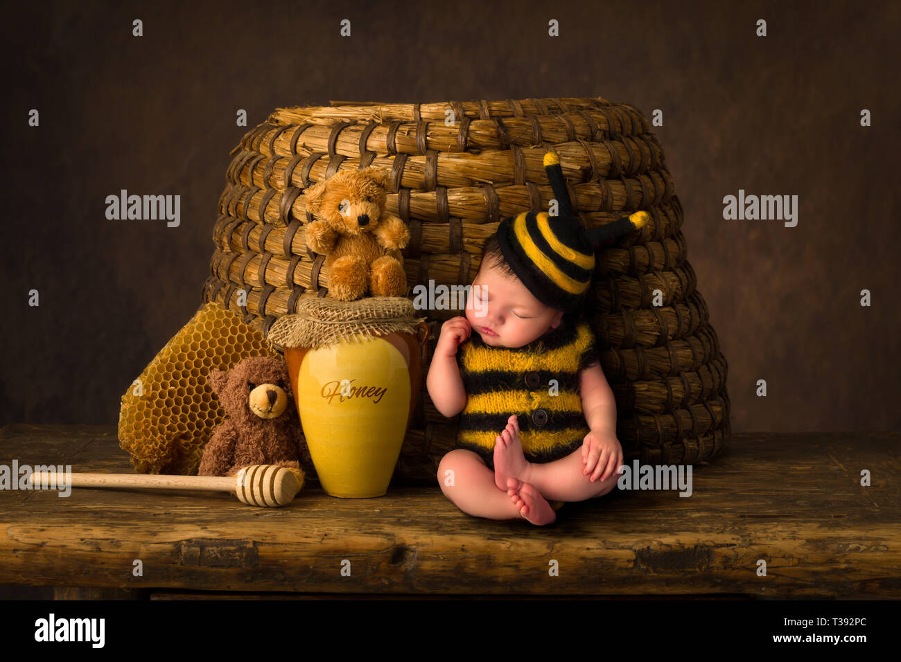 Sleepy cute baby in bee outfit resting against an antique beehive Stock ...