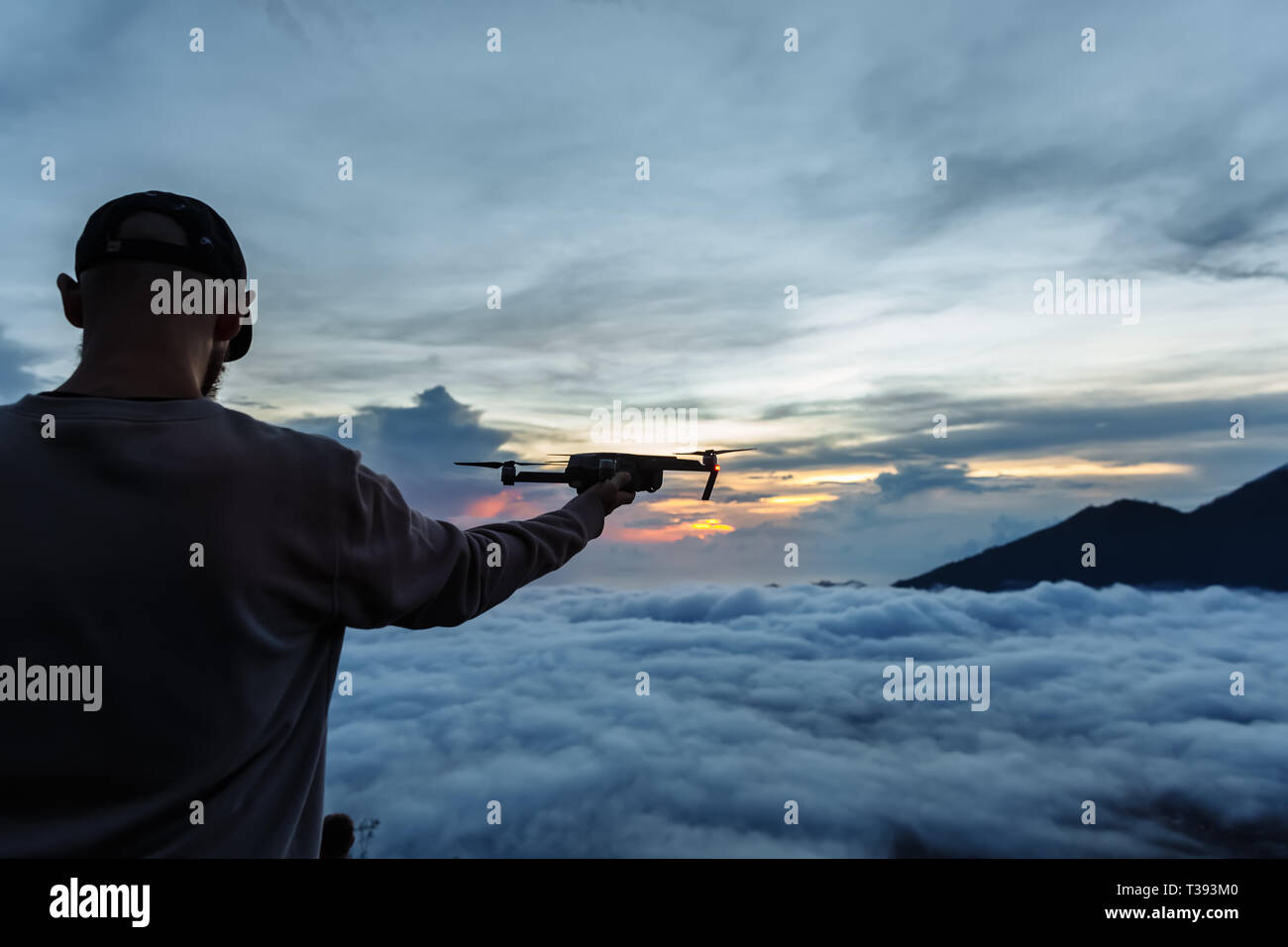 Man tourist looks at the sunrise on the volcano Batur on the island of ...
