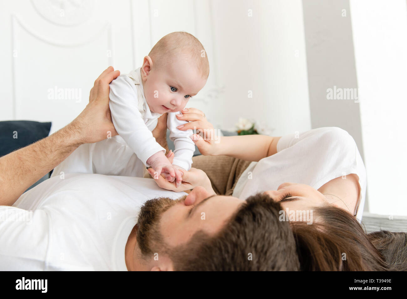 Young parents lay and hold baby girl Stock Photo - Alamy