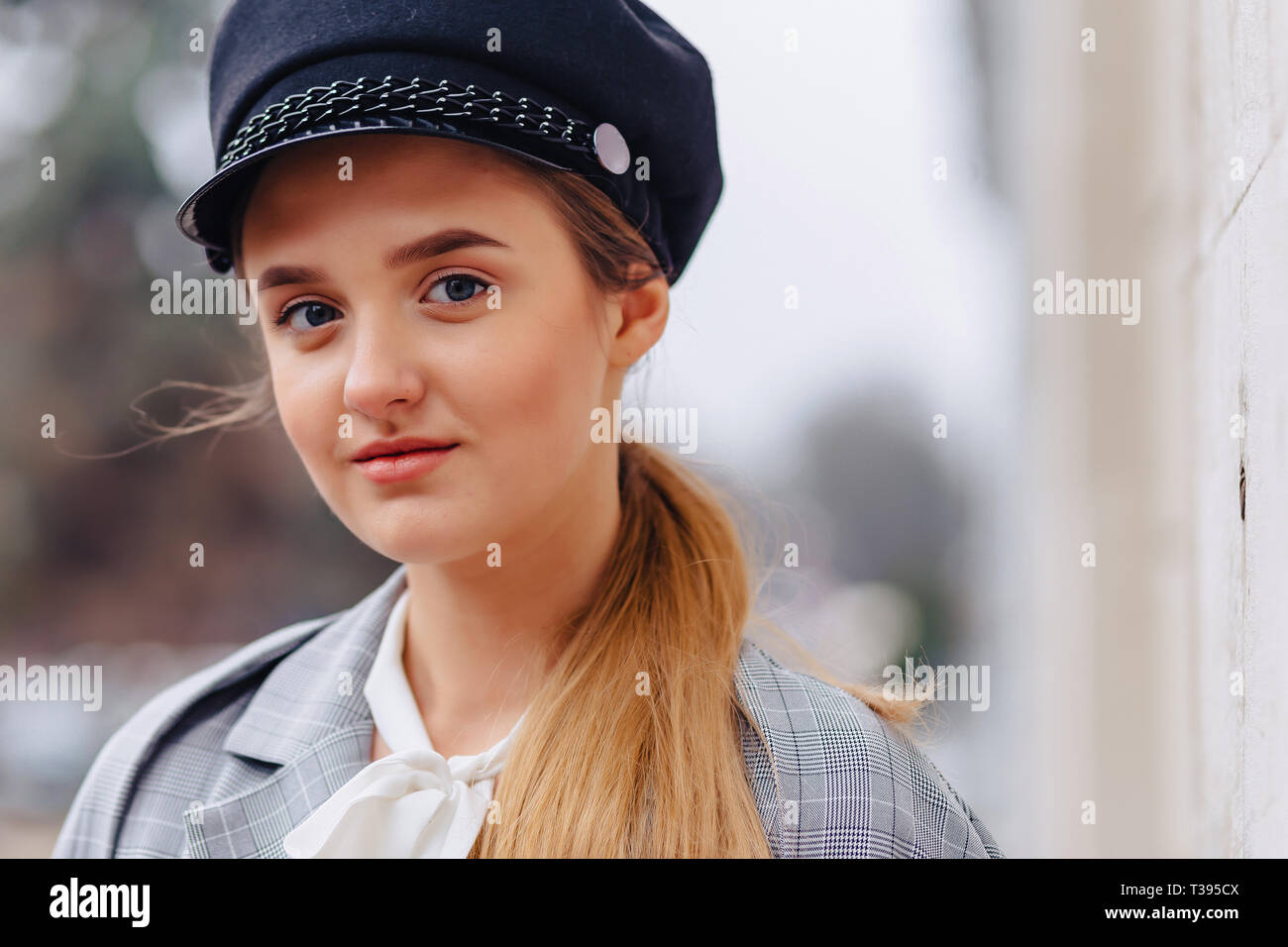 A cute, pretty girl in a stylish suit walks around the city and poses ...