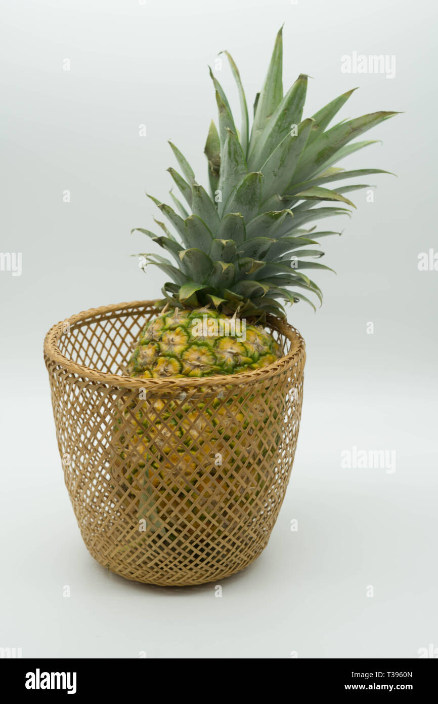 single pineapple standing in a wicker basket on an isolated white ...