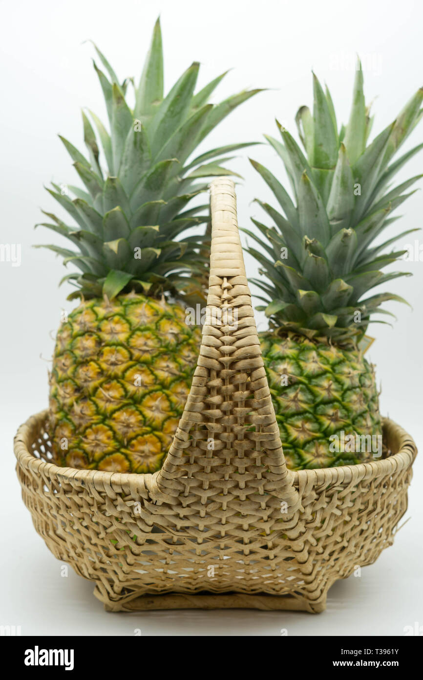 front view of two pineapples in a wicker basket Stock Photo - Alamy
