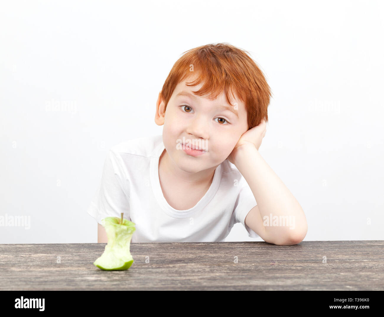 beautiful little boy and stub from the apple lying on a wooden table ...