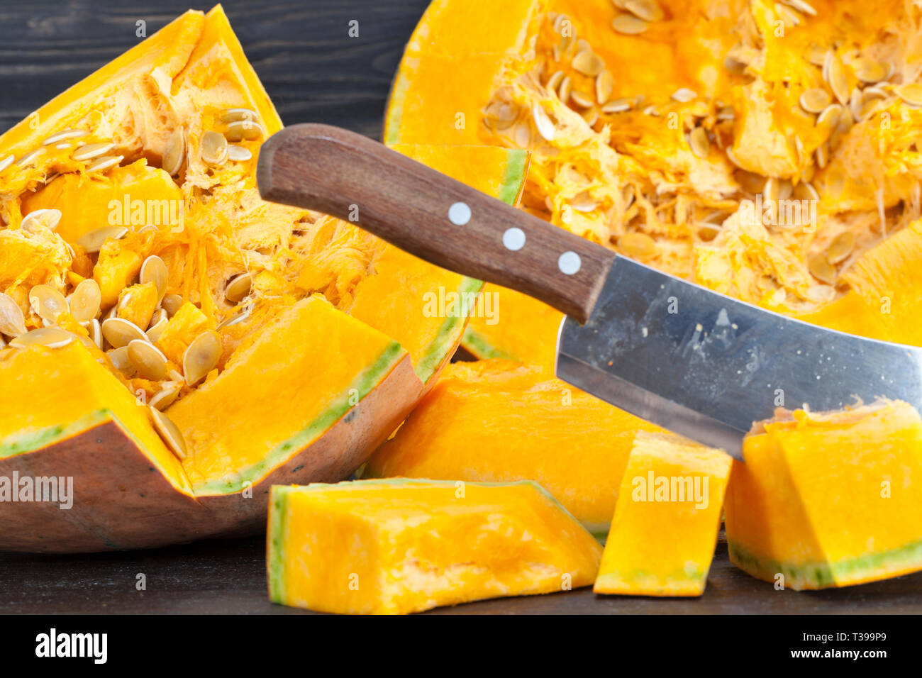 A large pumpkin sliced and chopped with a metal cleaver while cooking ...