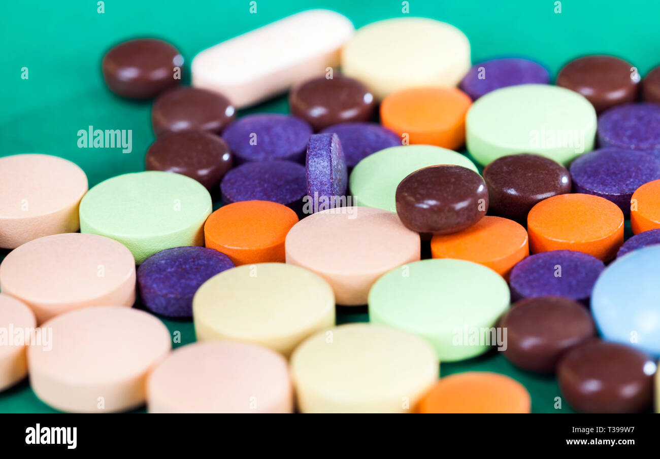 Multi-colored pills on a green background of various packs, a bunch of ...