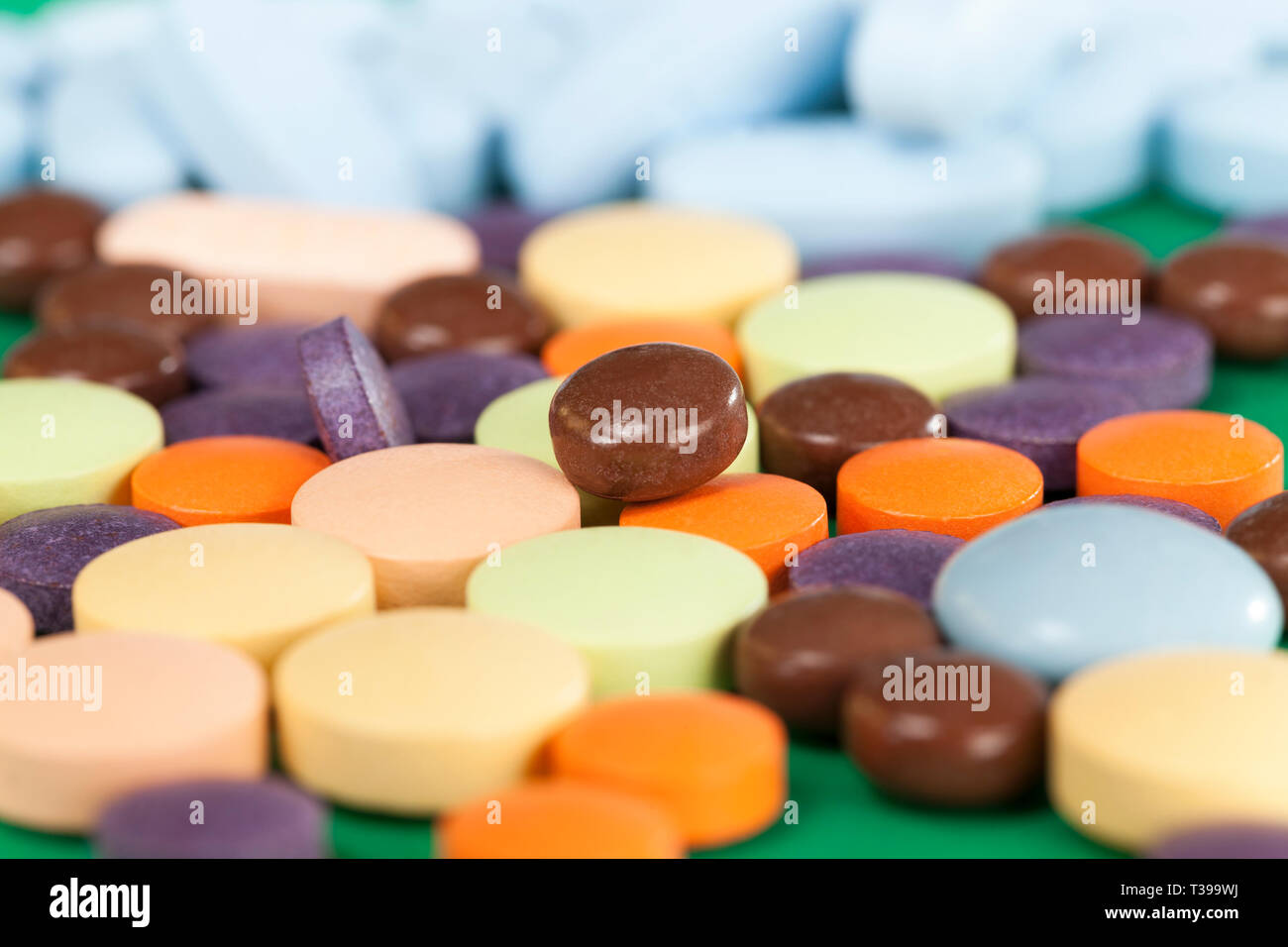 Multi-colored pills on a green background of various packs, a bunch of ...