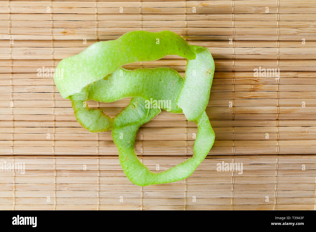 The shell of the green apple peel peeled and folded on a bamboo ...
