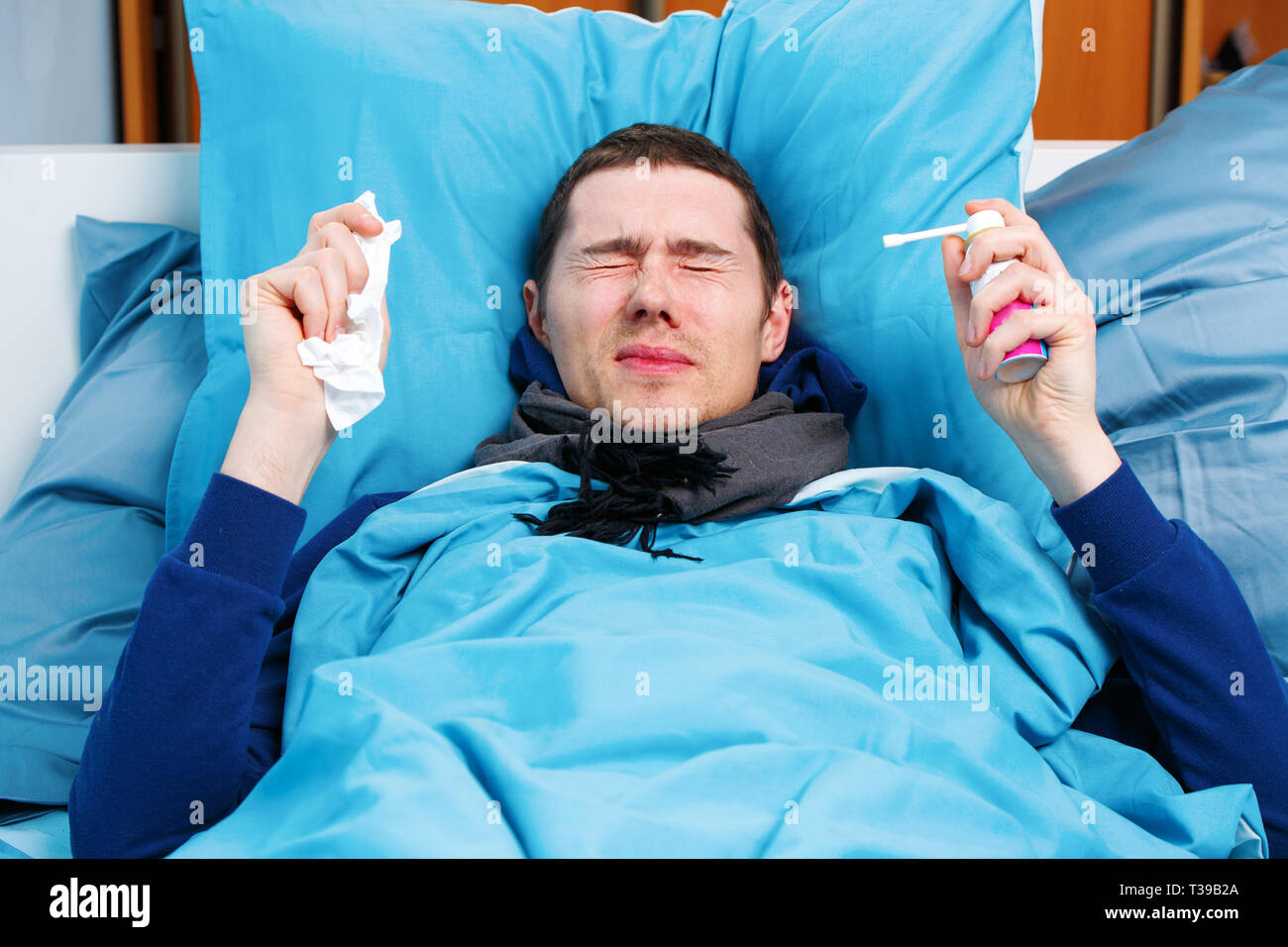 Photo of sick man in scarf with handkerchief and spray with medicine ...