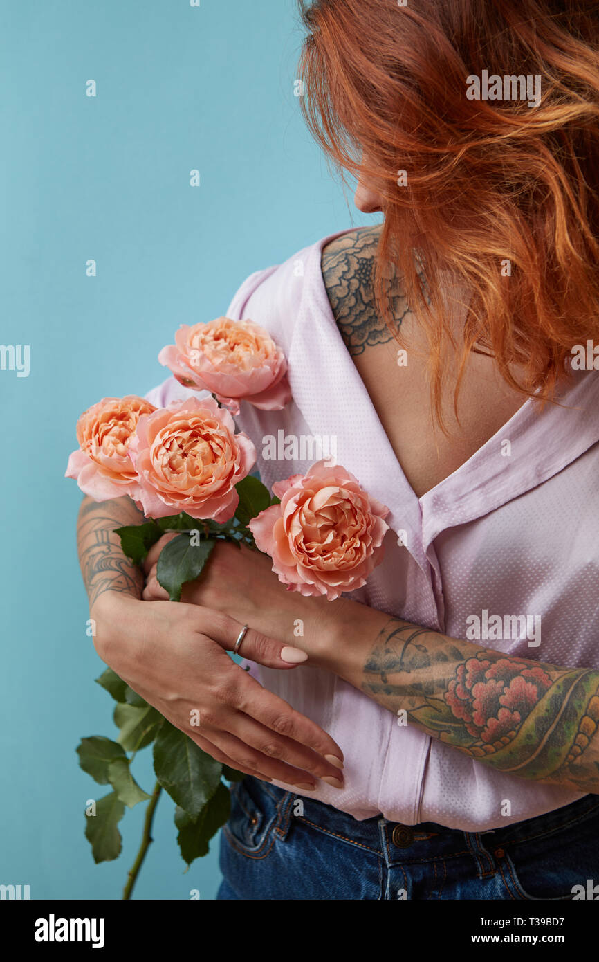 A girl with a tattoo on her hand holds delicate pink roses around a ...
