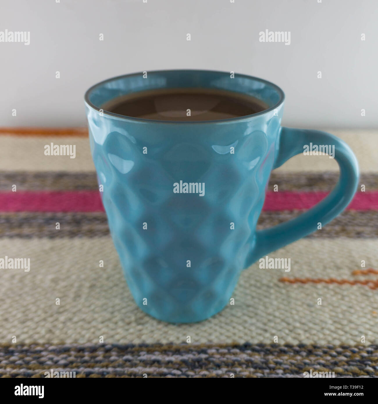 Turquoise Cup of coffee against the striped braided rug Stock Photo - Alamy