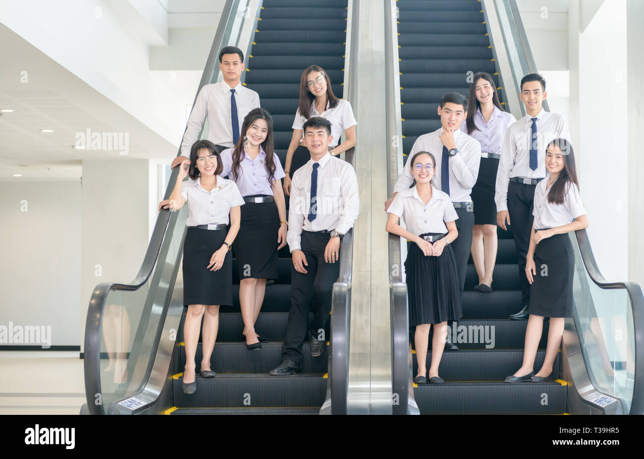 Smart young students standing together on escalator in university ...