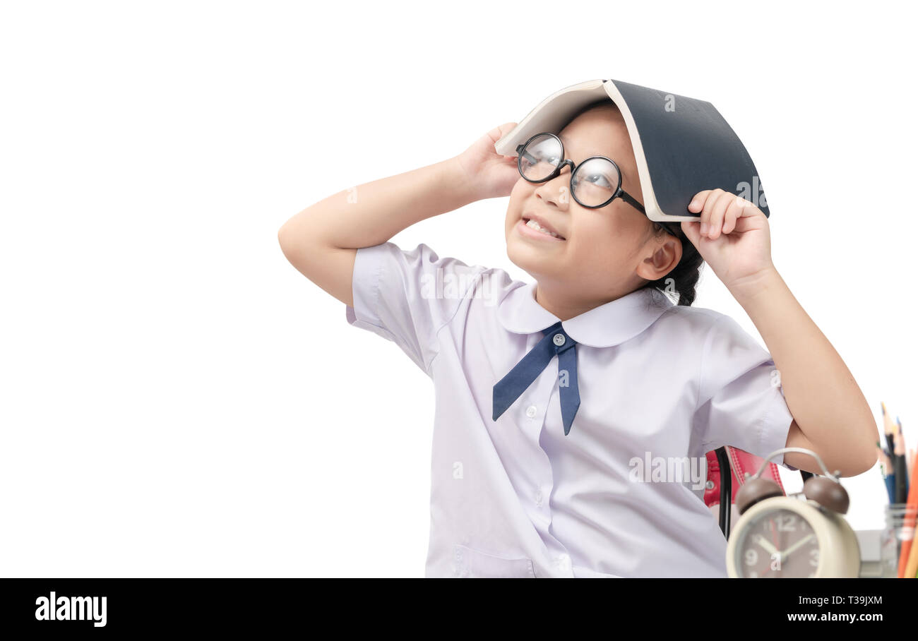 Smart little Asian girl thinking with book on head while doing homework ...