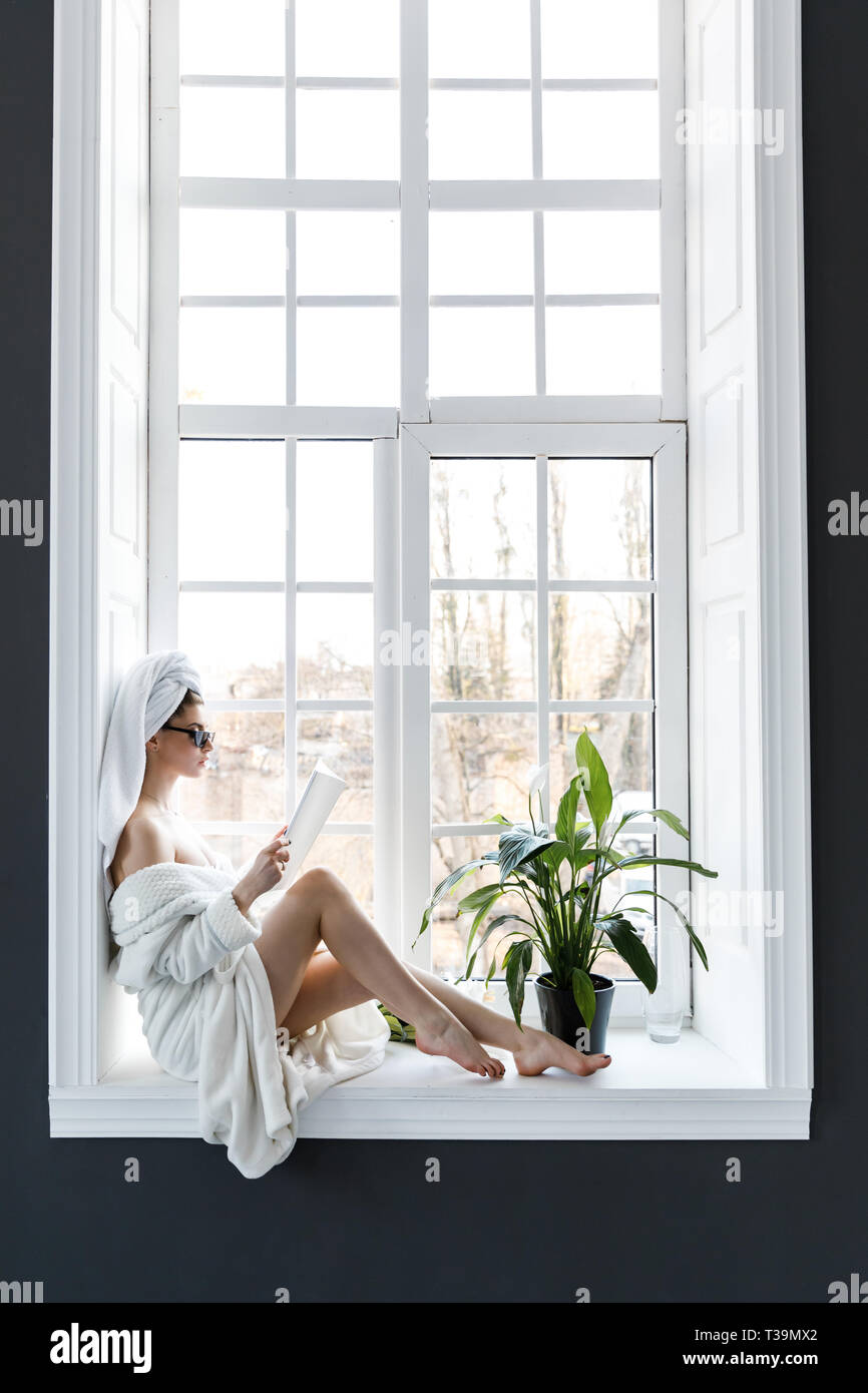 A cute young woman dressed in a white robe and with towels on her head ...