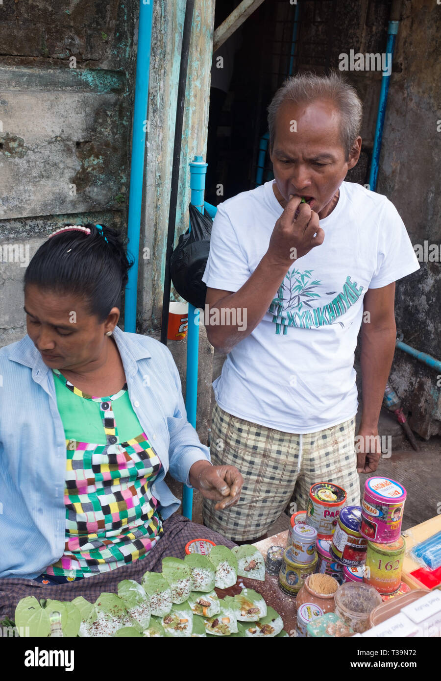 street vendor selling Paan (betel chewing) to a waiting customer , a ...
