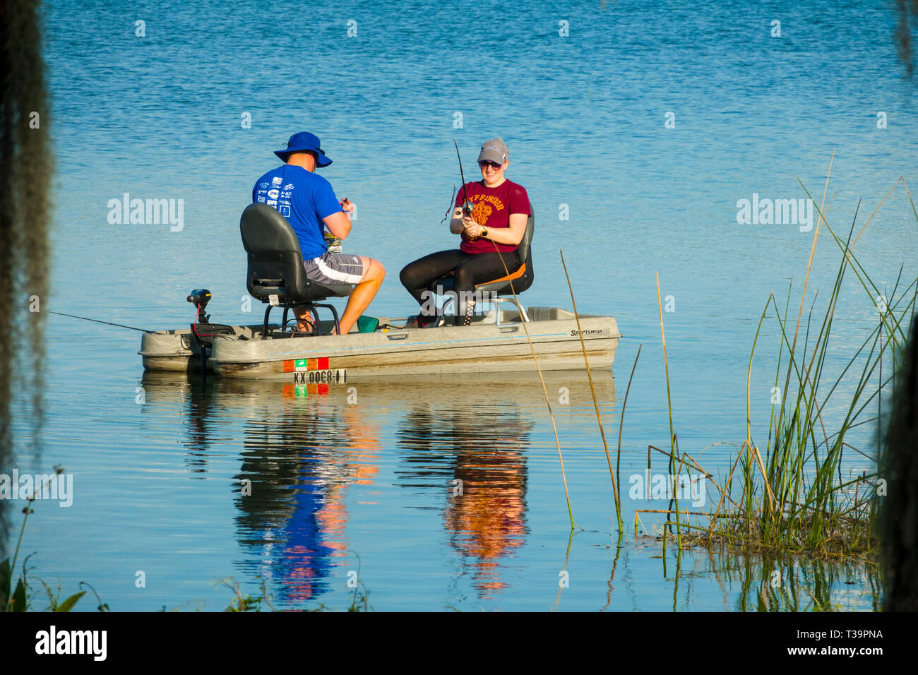 Husband and wife fishing from a small boat together for bass fish on ...