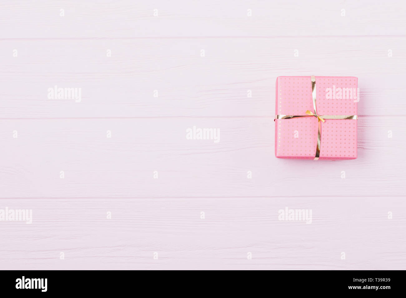 View from above one gift box wrapped in pink paper with golden ribbon ...
