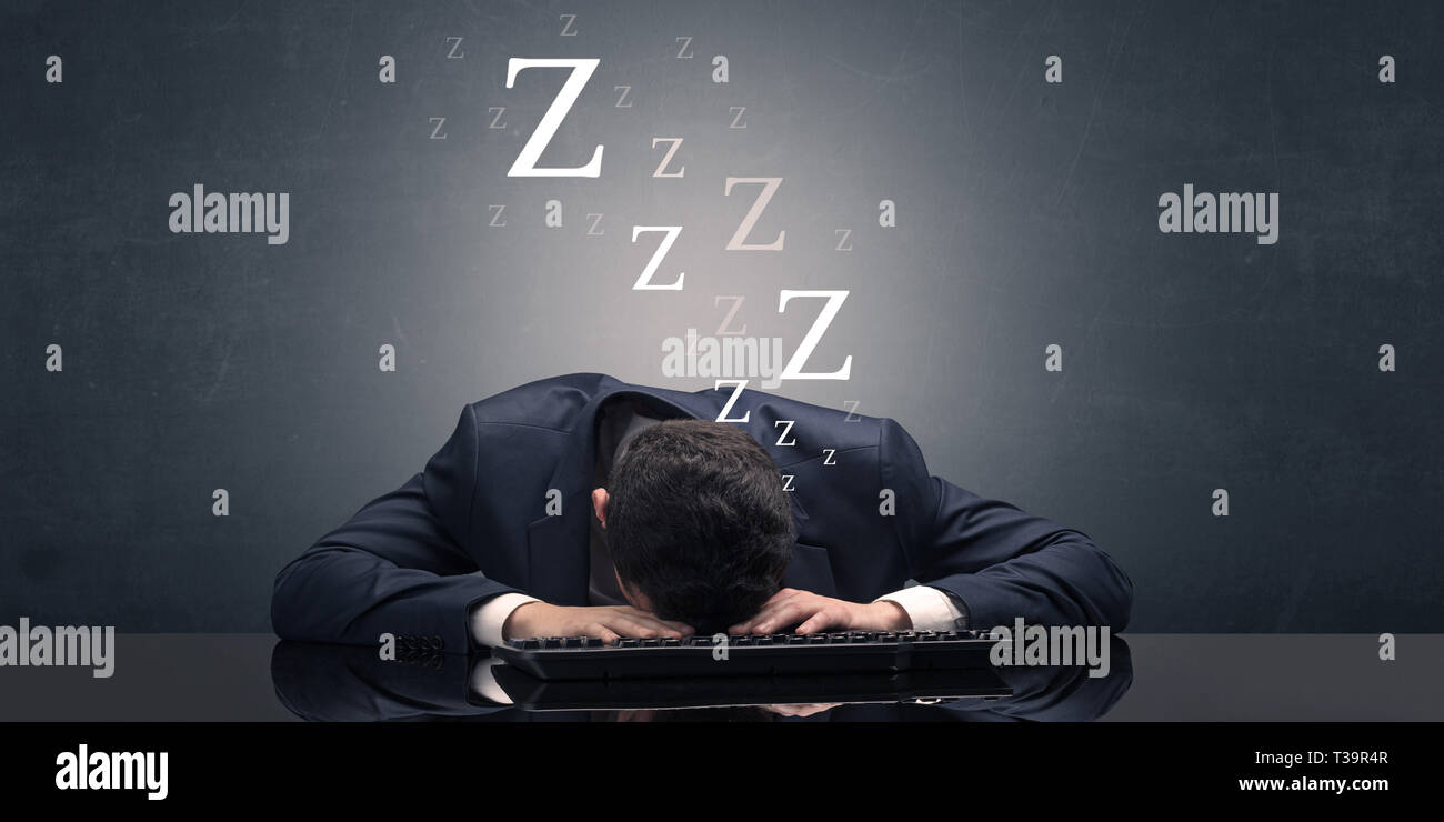 Young businessman fell asleep at the table on his keyboard concept ...