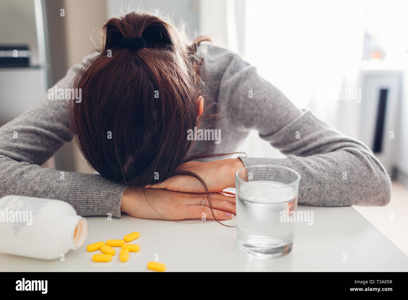 Young woman upset and tired of taking pills against illness on kitchen ...