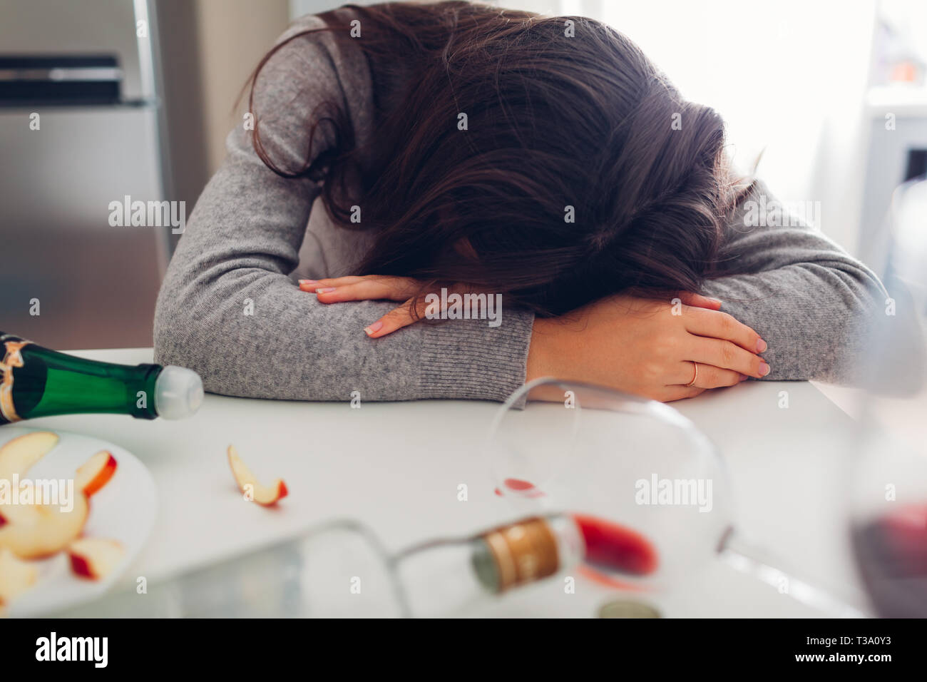 Female alcohol addiction. Young woman sleeping on kitchen table ...
