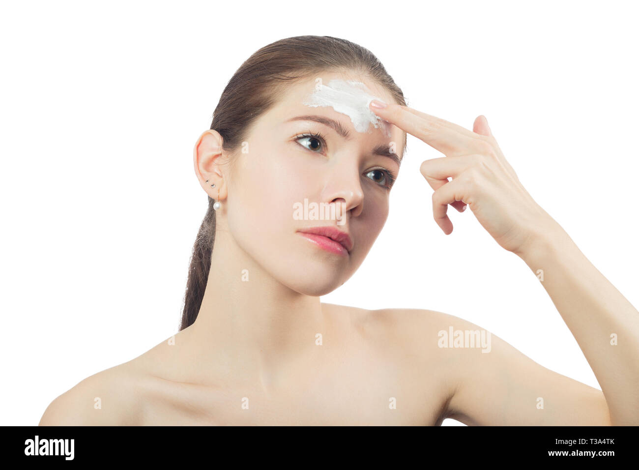 serious young woman applying cream on her face skin, isolated on white ...
