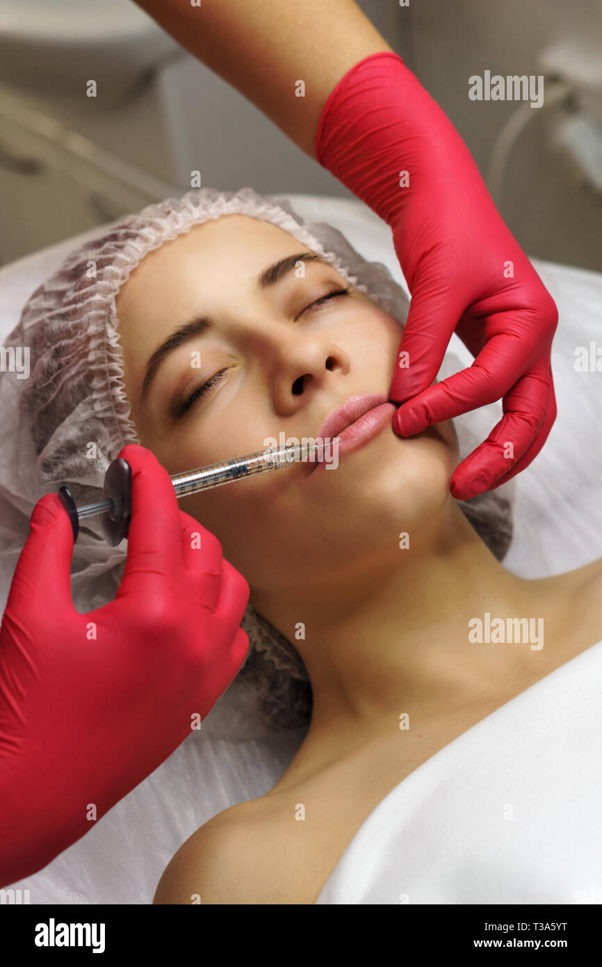 Рands of beautician make injections into face and lips of girl. Young ...