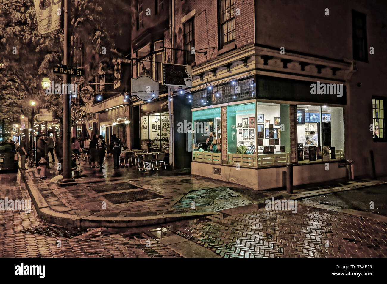 A brick laid street corner with a downstairs restaurant and a crowd of ...