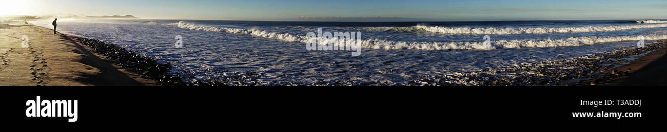 Horizontal panorama of a man looking out across a surf break Stock ...