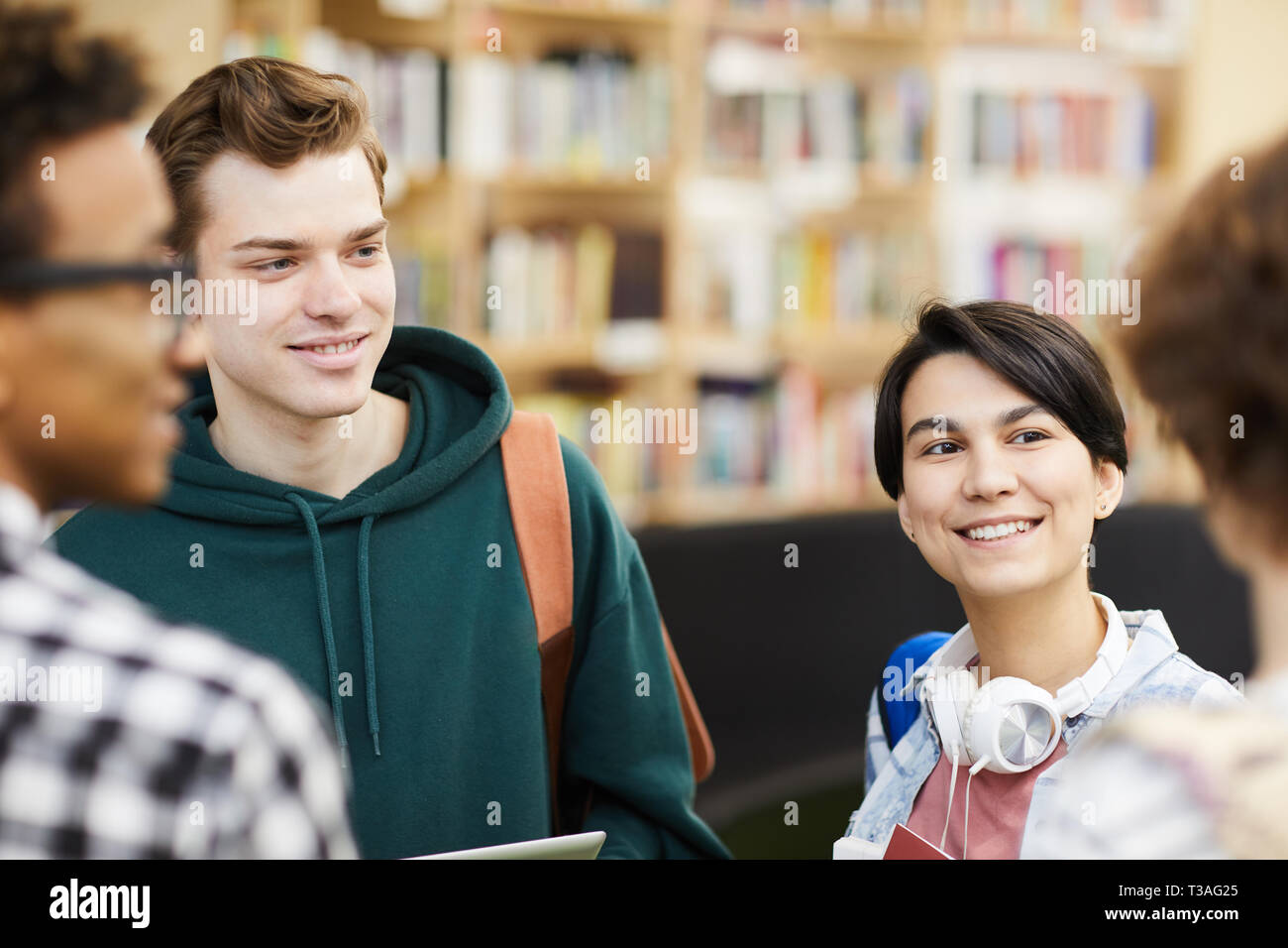 Positive students chatting in library Stock Photo - Alamy