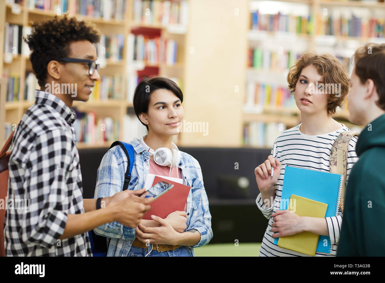 Multiethnic university students talking in library Stock Photo - Alamy