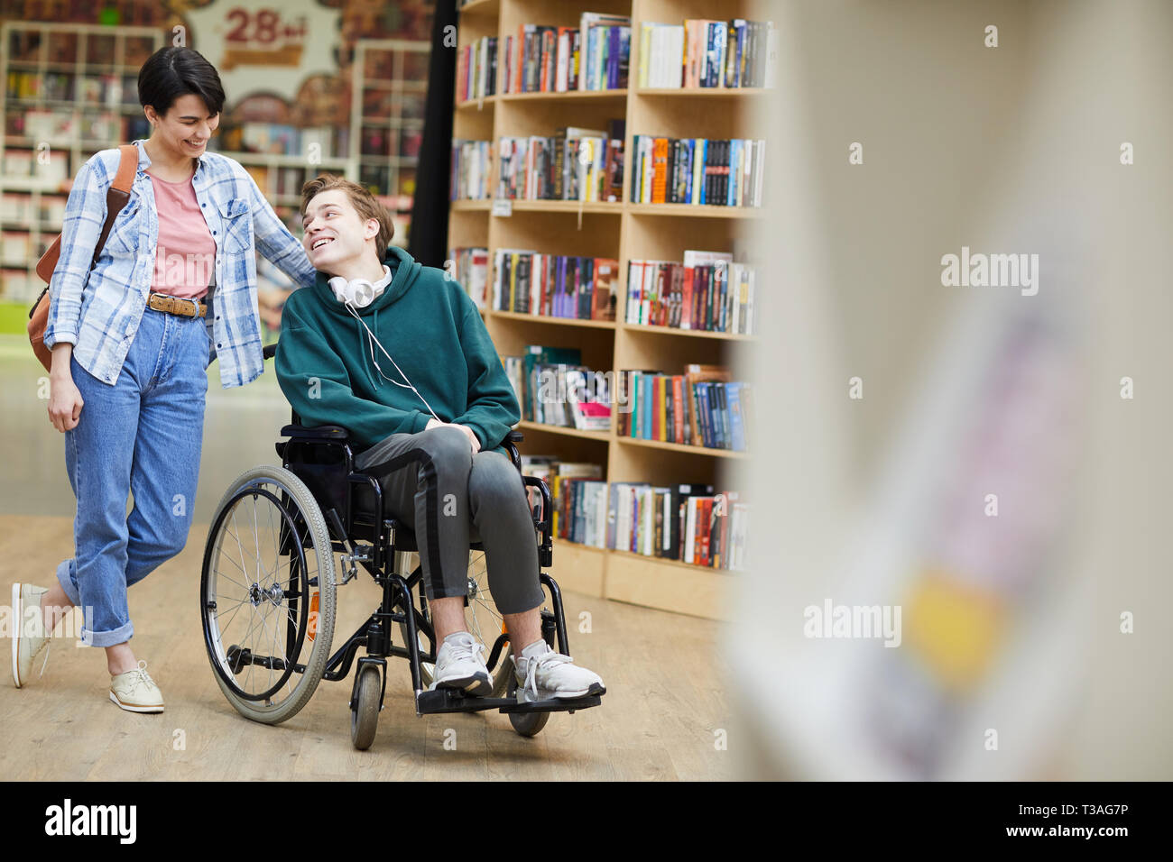 Disabled student visiting library with groupmate Stock Photo - Alamy