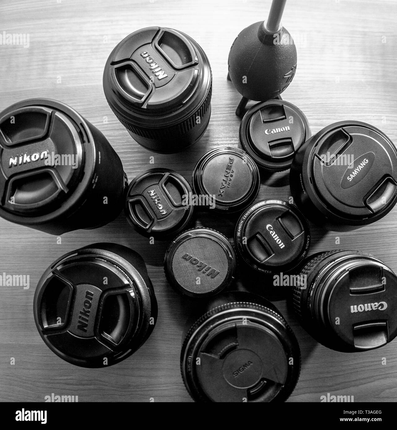 An array of assorted DSLR lenses arranged on a flat wooden table top ...