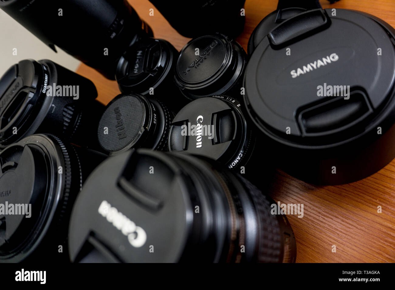 An array of assorted DSLR lenses arranged on a flat wooden table top ...