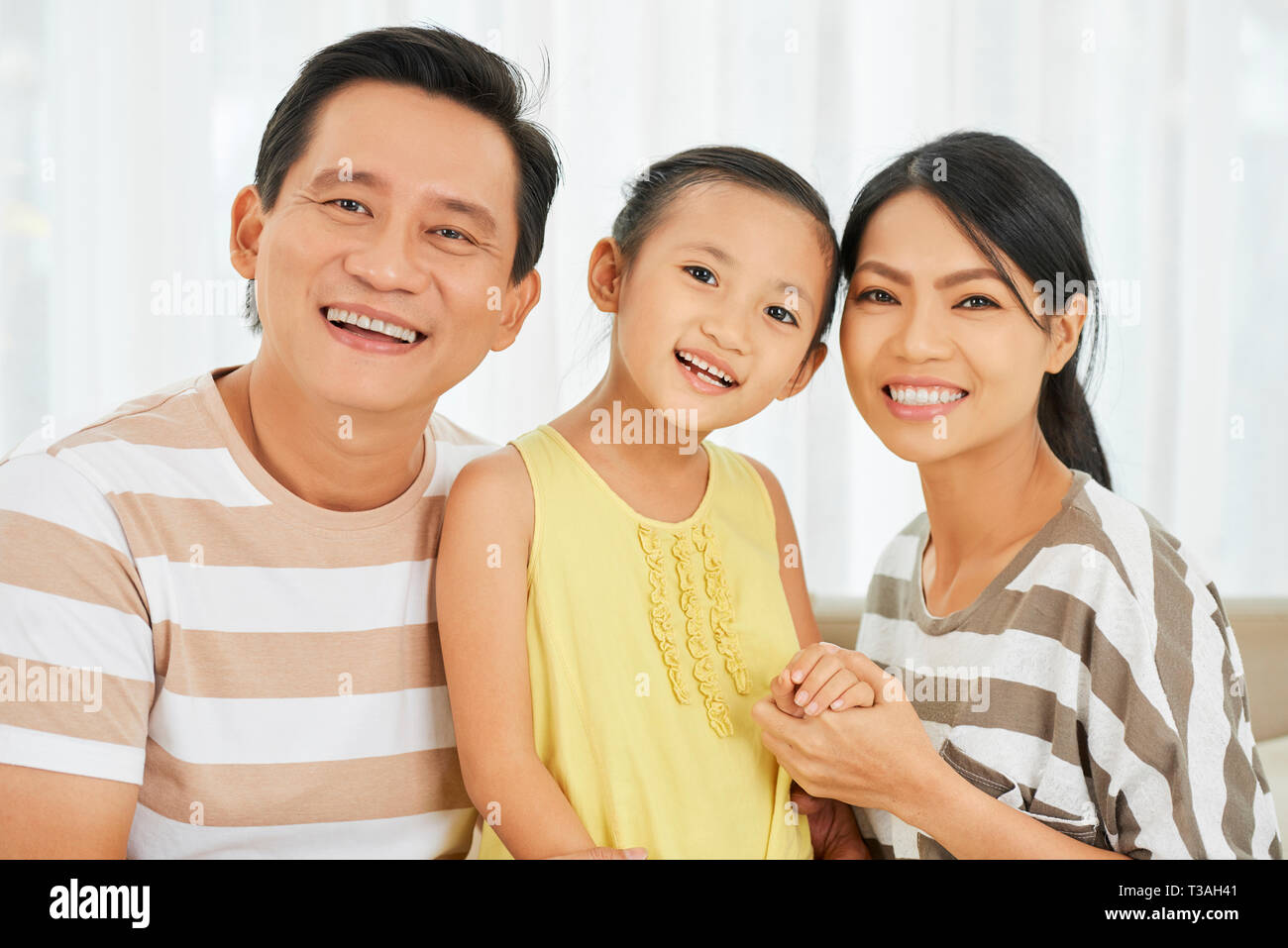 Portrait of smiling Asian family of mother, father and little daughter ...