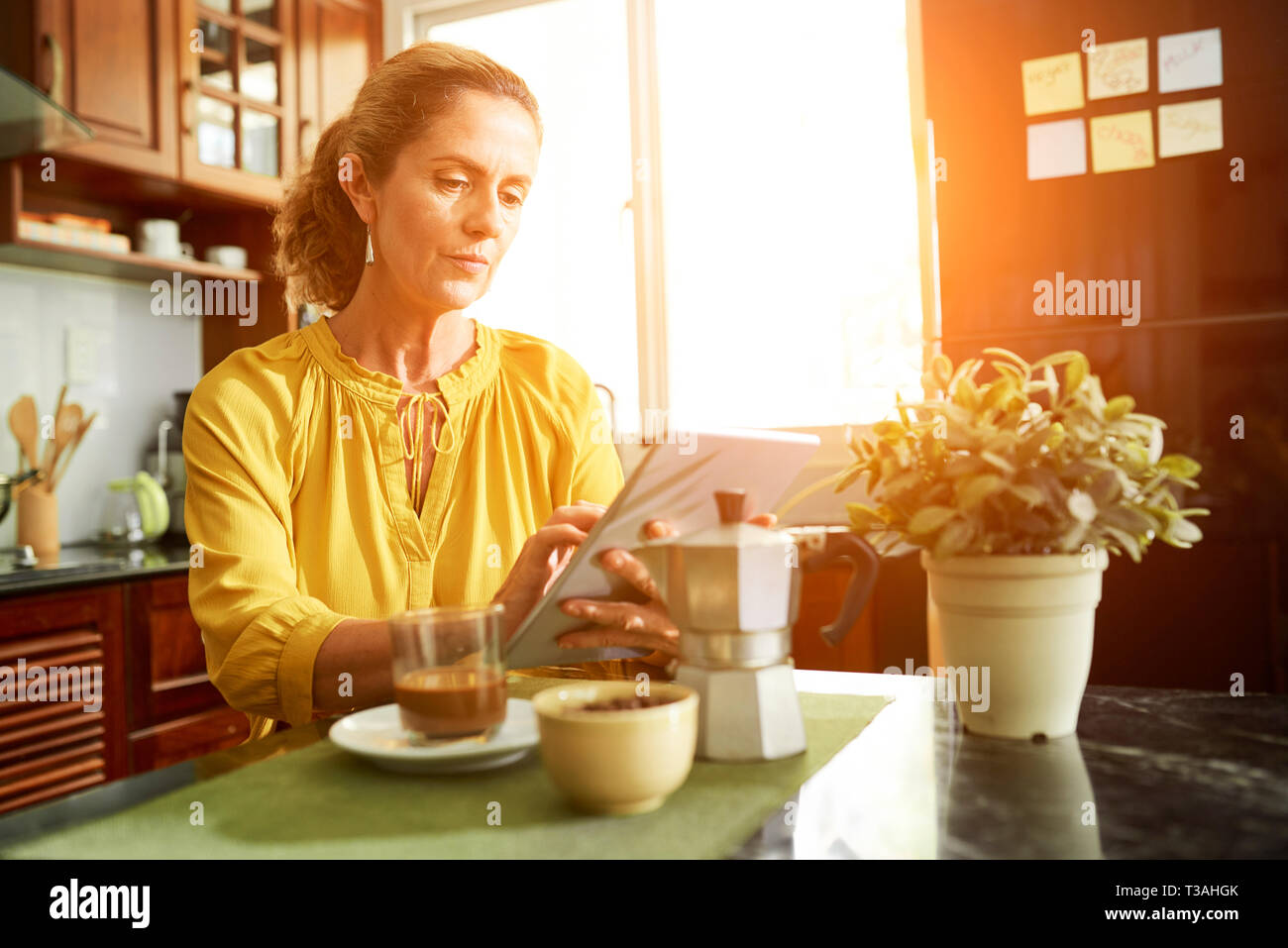 Mature woman sitting on kitchen table hi-res stock photography and ...