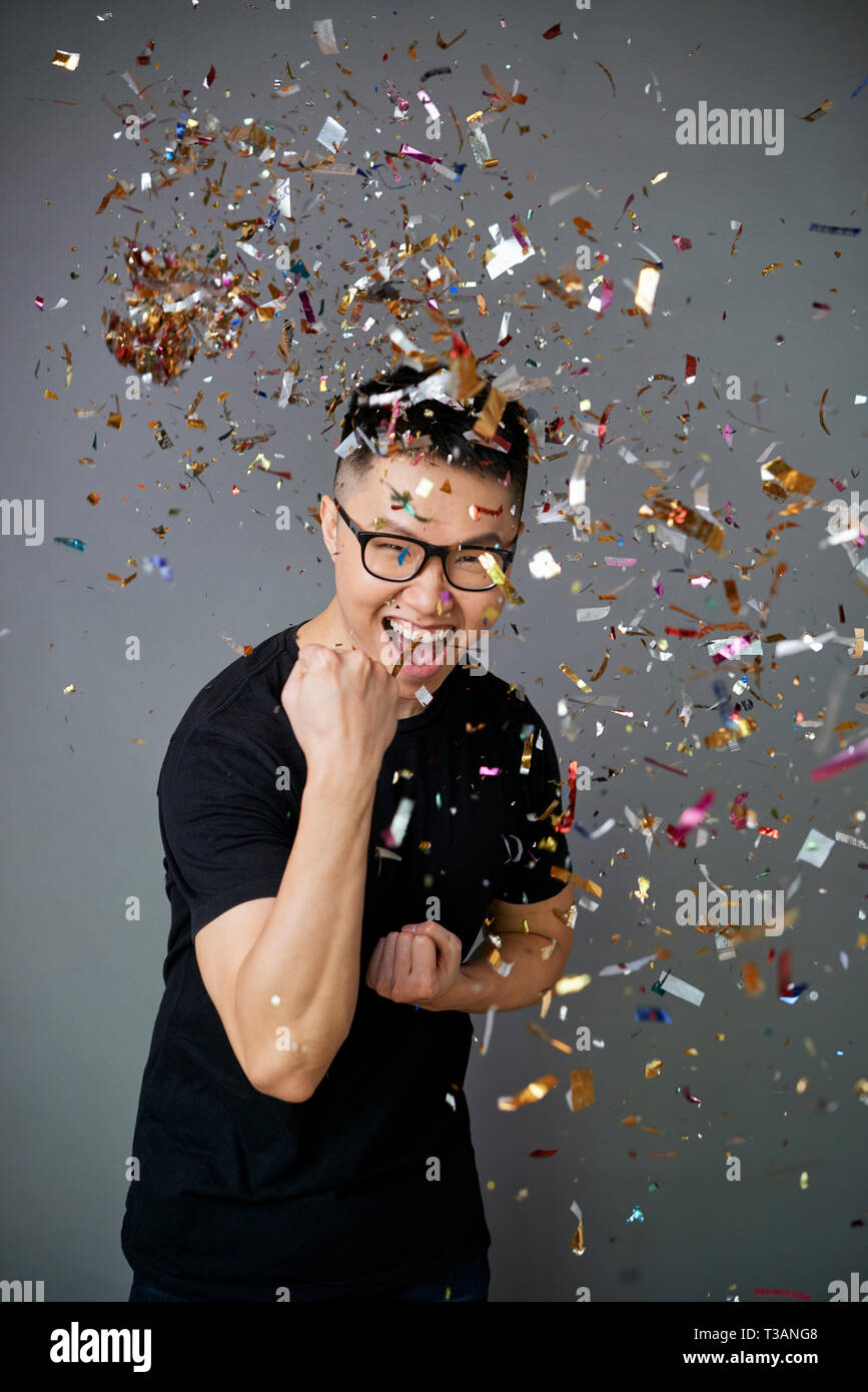 Young man under falling confetti Stock Photo - Alamy
