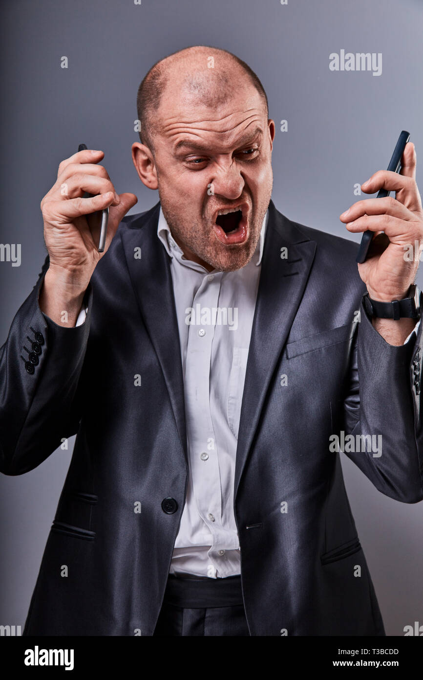 Unhappy loud crying anger business man talking on two mobile phones ...