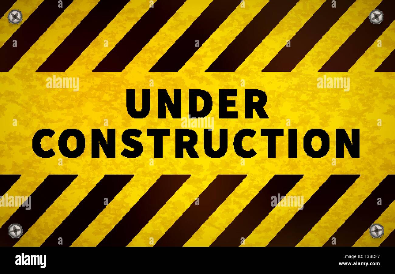 Bright yellow under construction warning sign with metal screws in ...