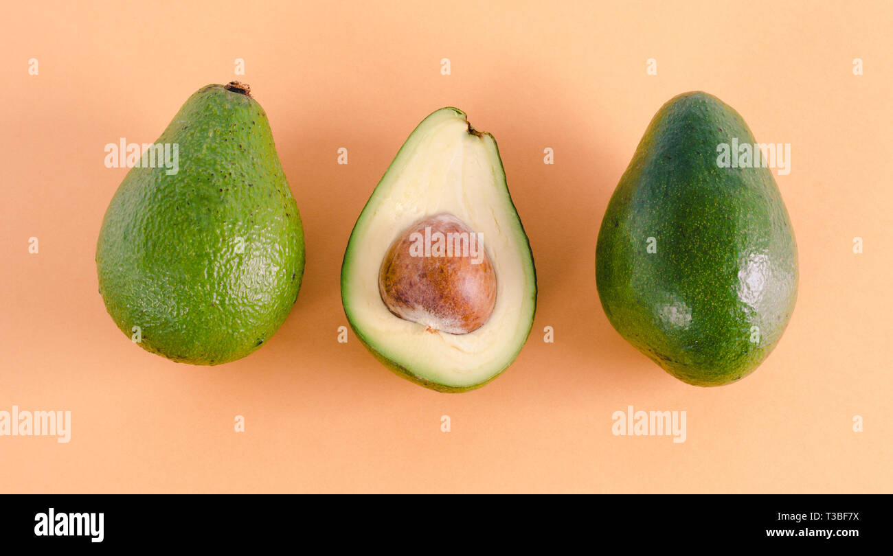 Two avocados and half of another on colored background. Top view Stock ...