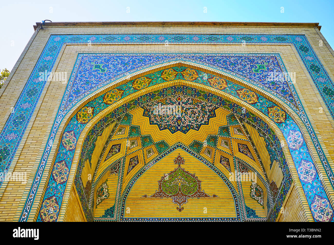The brick muqarnas arch with intricate tile patterns decorates the ...