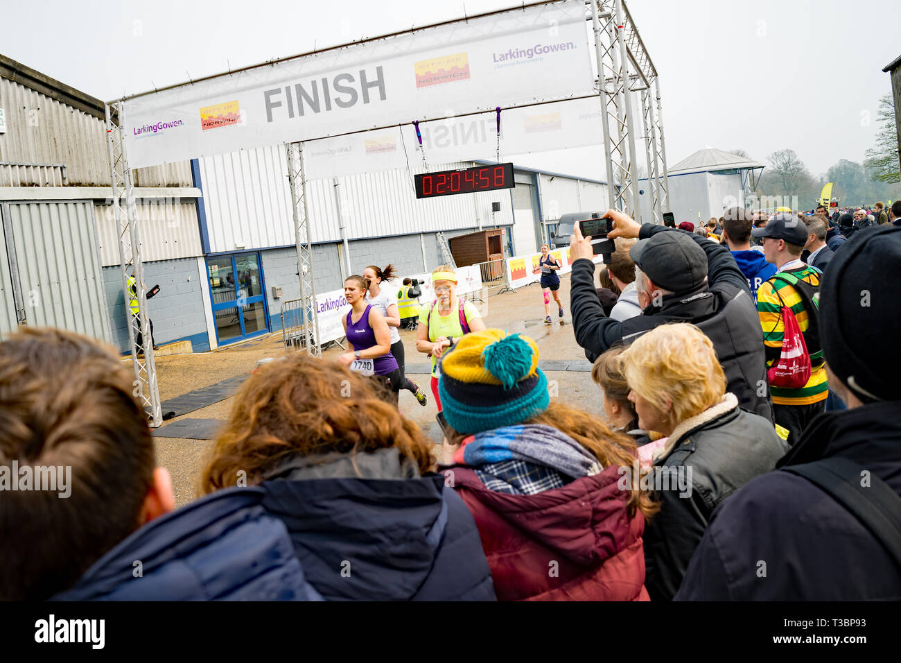 Spectators standing at the finish line of the Norwich half marathon ...