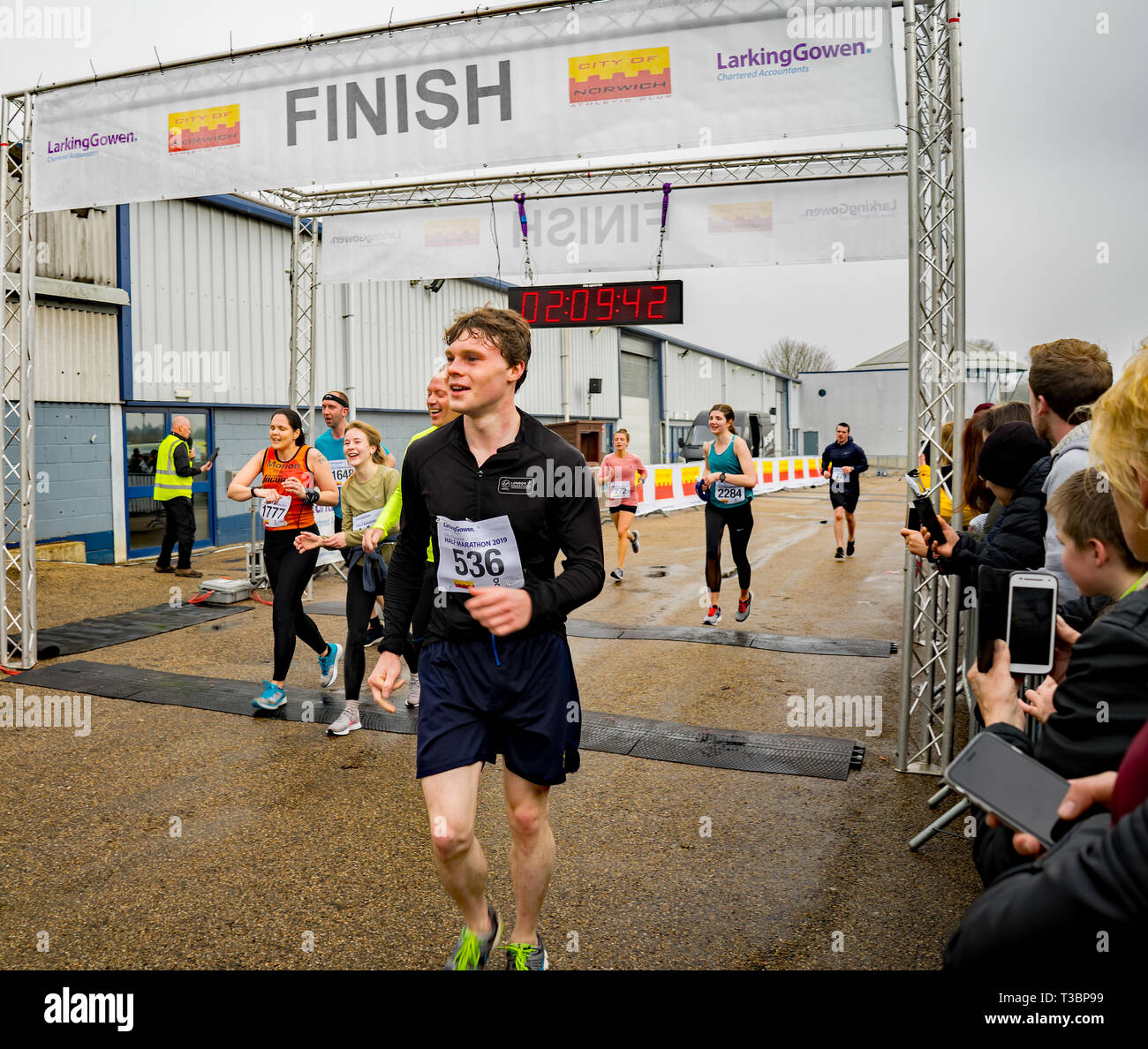 A young male runner dressed in black athletic clothing completing the ...