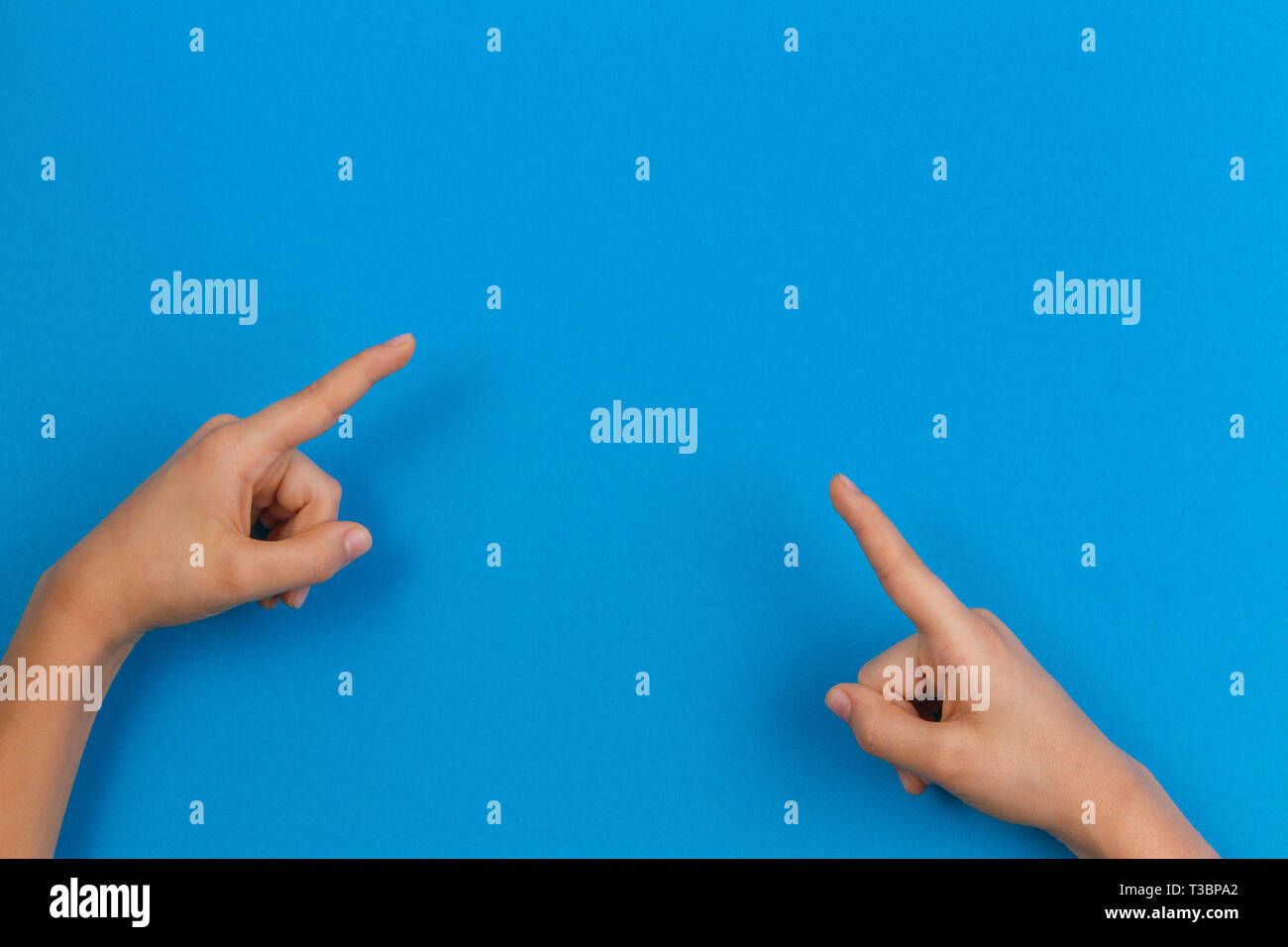 Kid hands pointing to something on blue background Stock Photo - Alamy