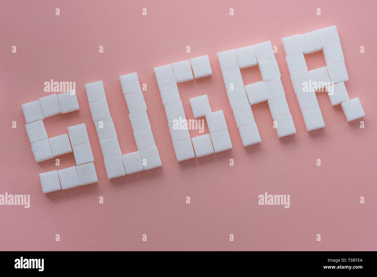 Sugar cubes used to spell the word sugar on a pink background Stock ...
