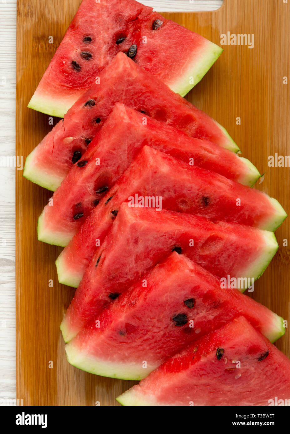 Sliced fresh ripe watermelon on cutting bamboo board over white wooden ...