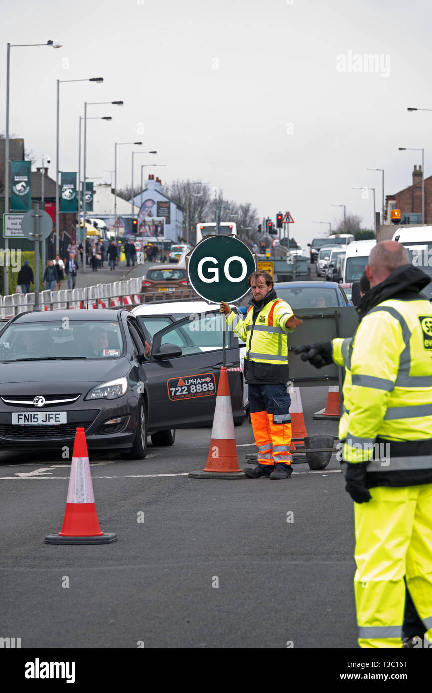 Workmen manually controlling traffic with stop and go signs Stock Photo ...