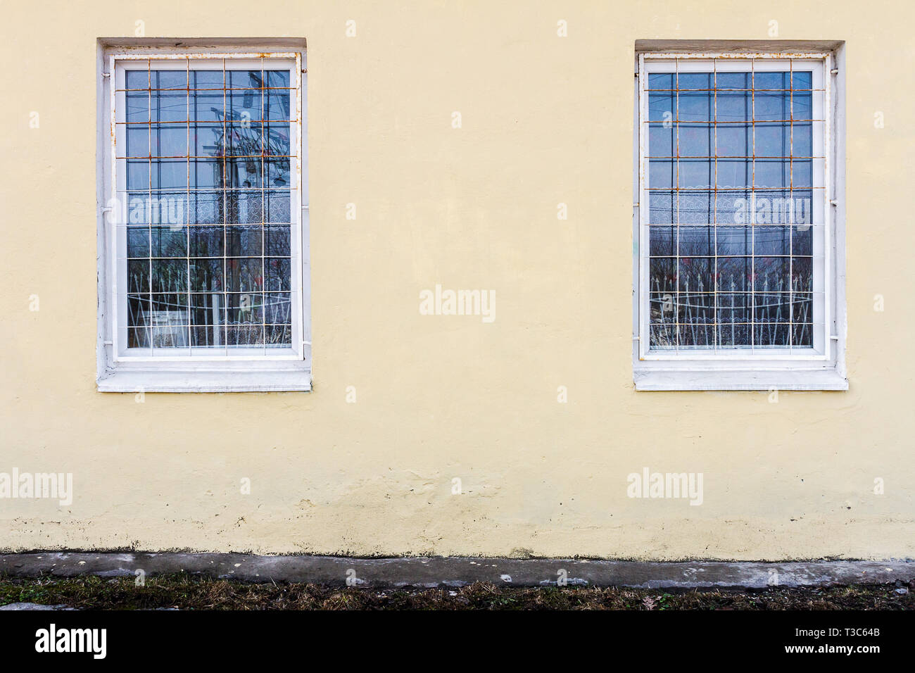Yellow street wall with two windows protected by grating Stock Photo ...