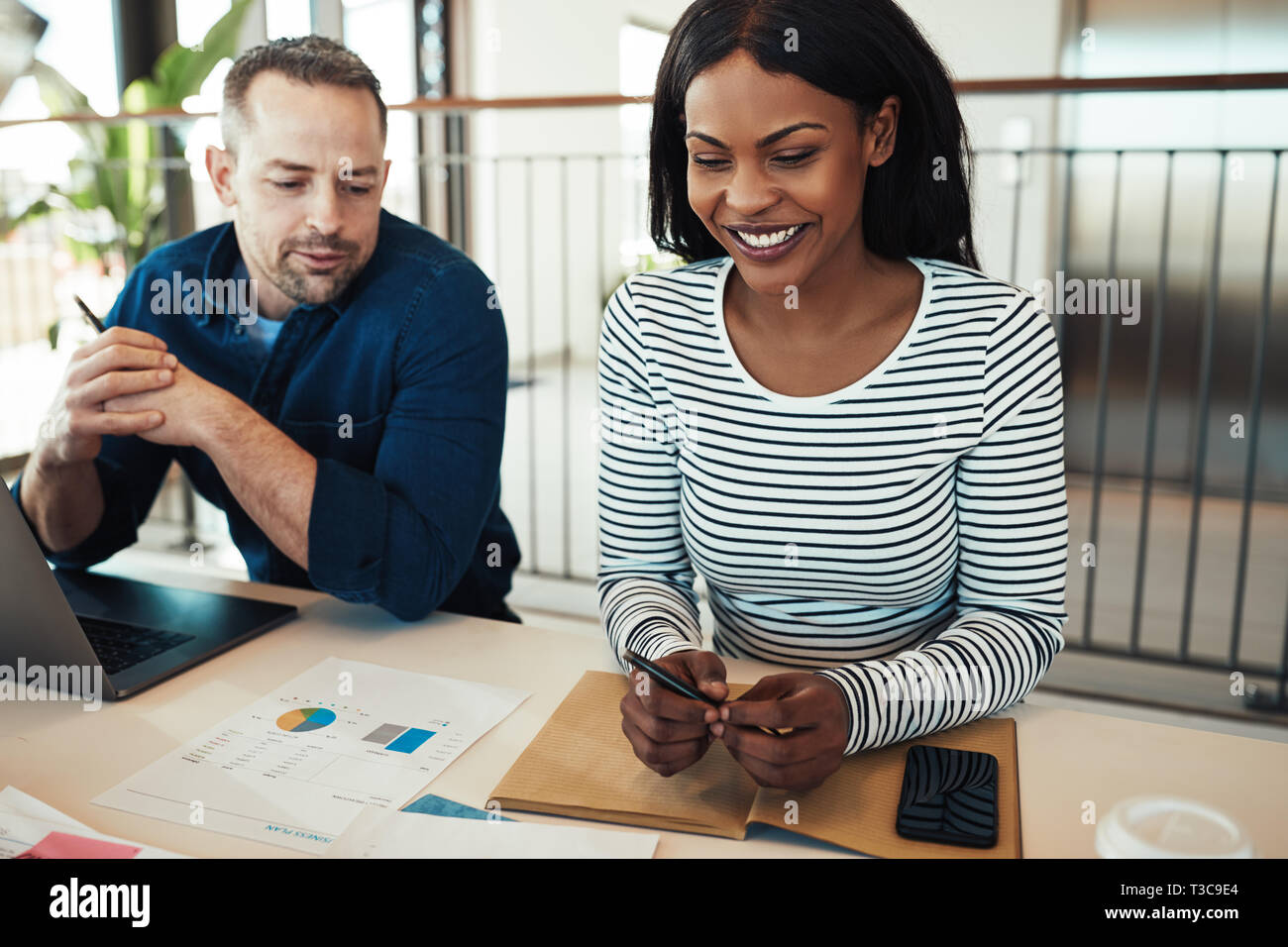 Two diverse business colleagues smiling and discussing paperwork ...
