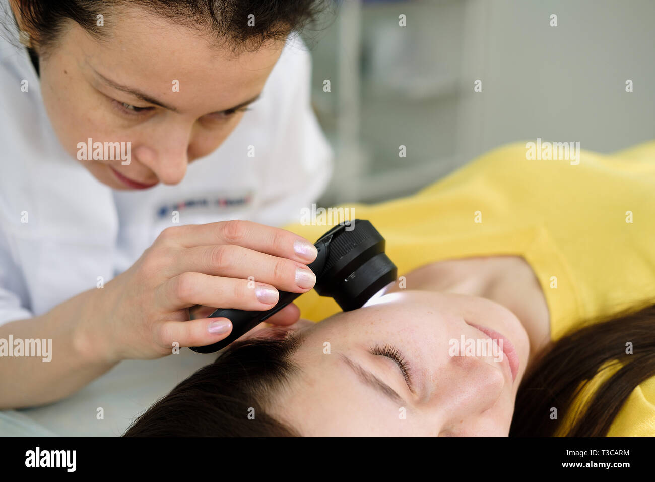 Female dermatologist using a professional dermatoscope while doing skin ...